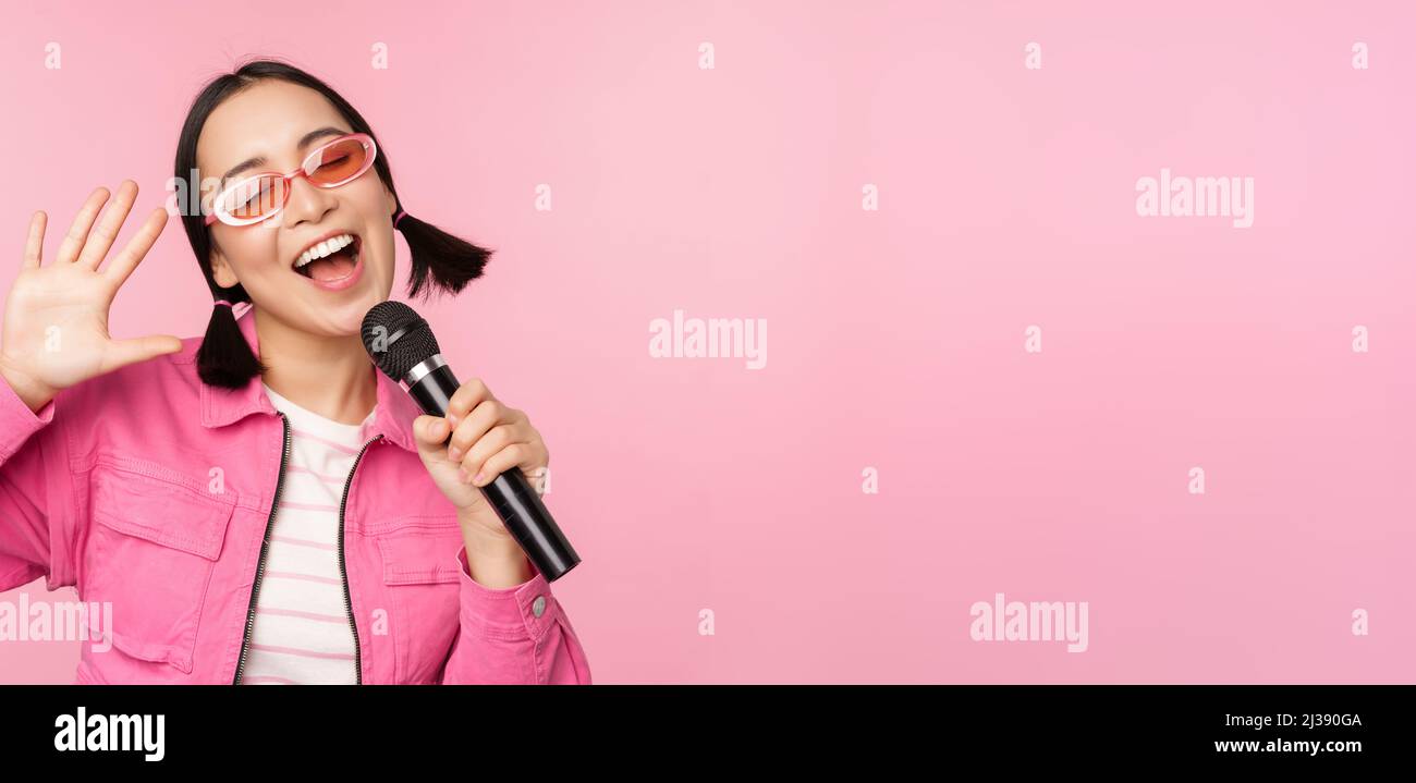 Happy beautiful asian girl singing with mic, using microphone, enjoying ...
