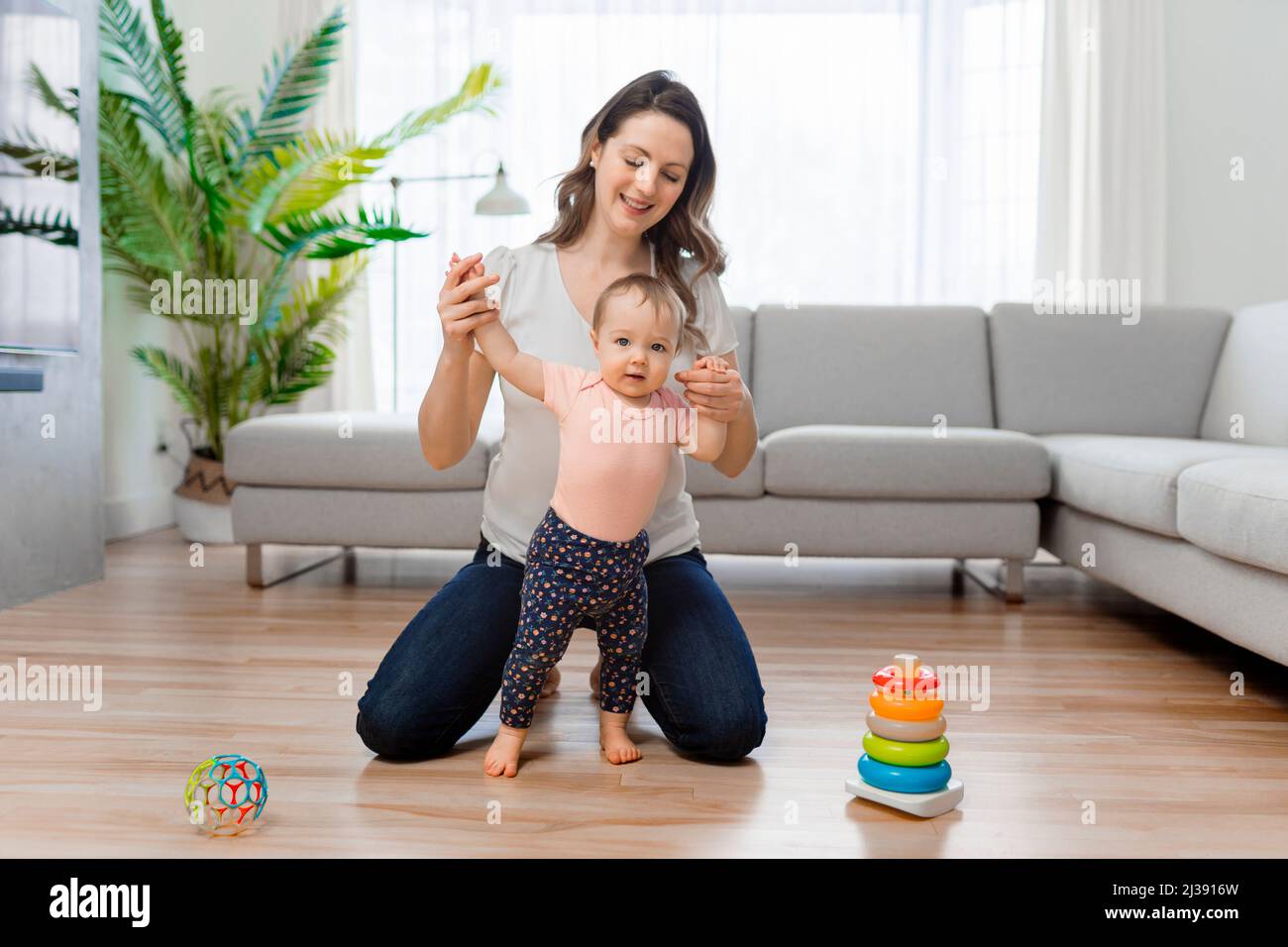 woman playing with her baby in the living room trying walking Stock ...