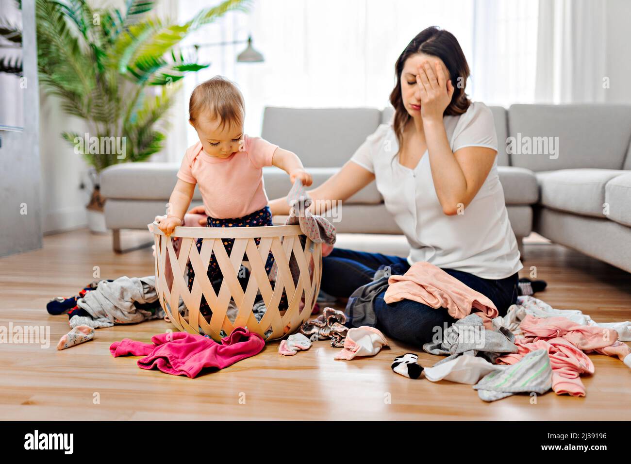 woman have problem choosing clothes with baby in the living room Stock ...