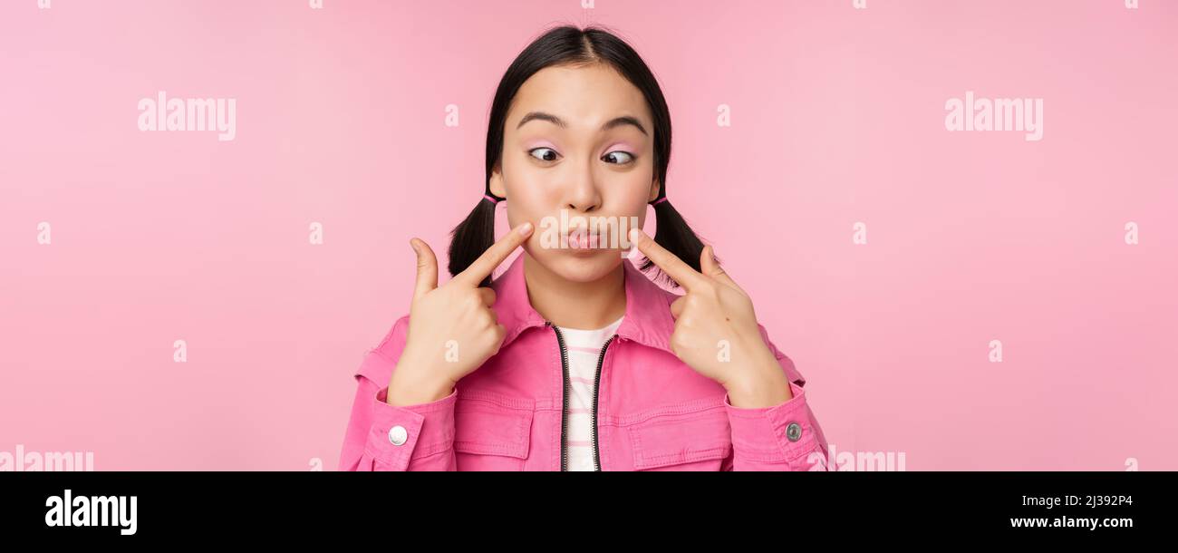 Close up portrait of young asian girl showing her dimples, poking ...