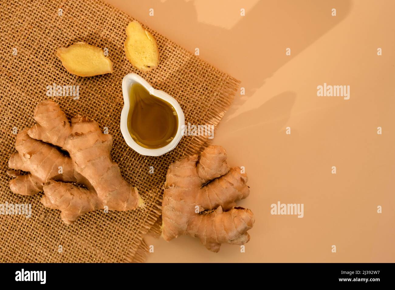 Sauce bowl of cooking ginger oil, ginger root on beige background ...