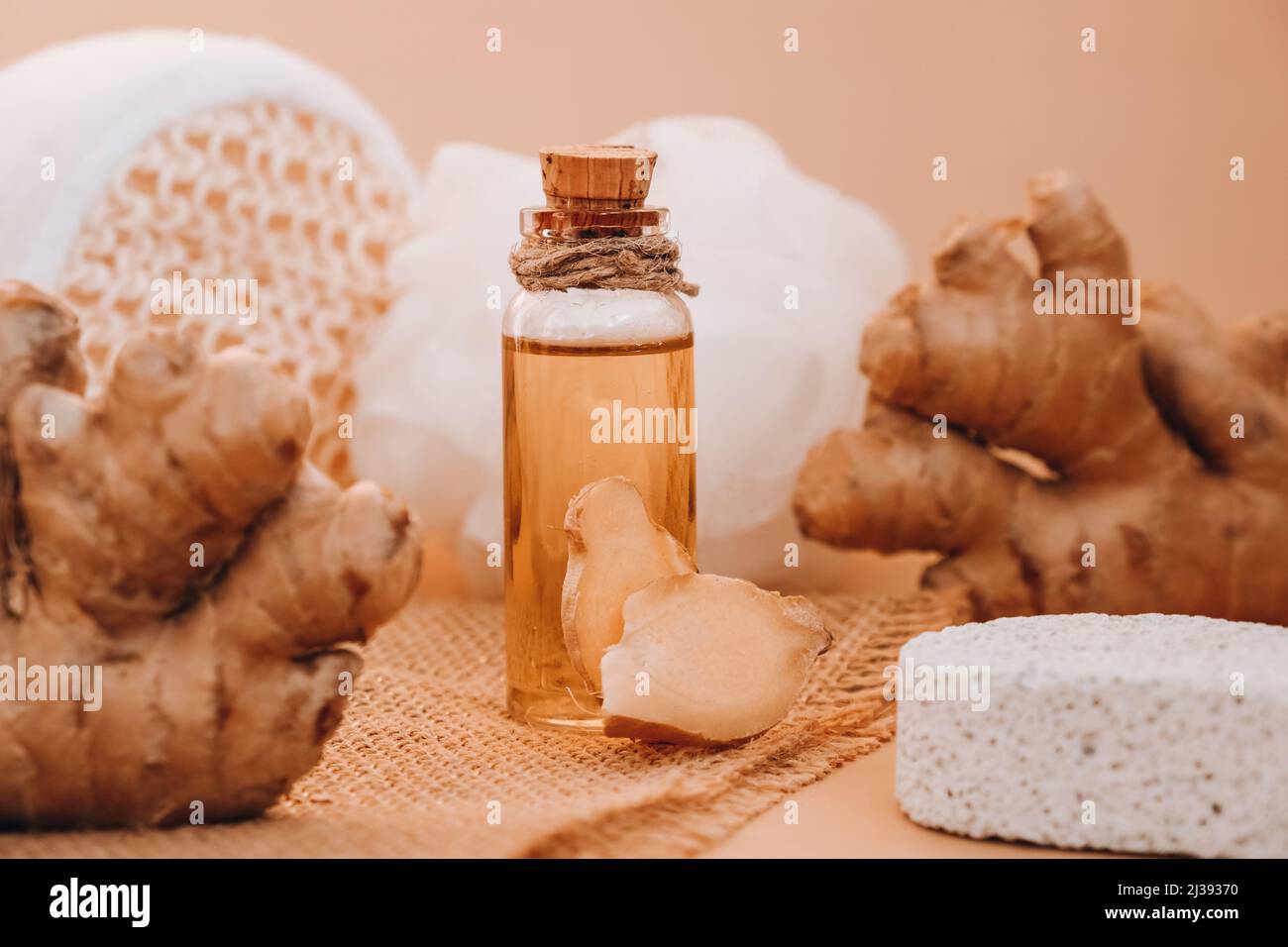 Glass bottle of essential ginger oil, ginger root on beige background ...