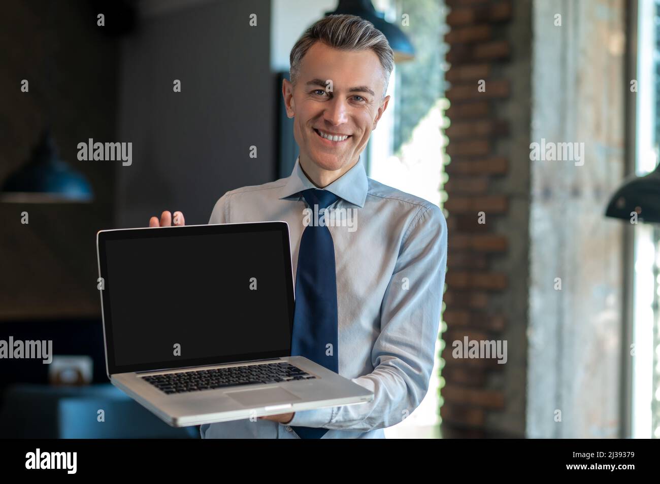 A smiling businessman showing his device and smiling Stock Photo - Alamy