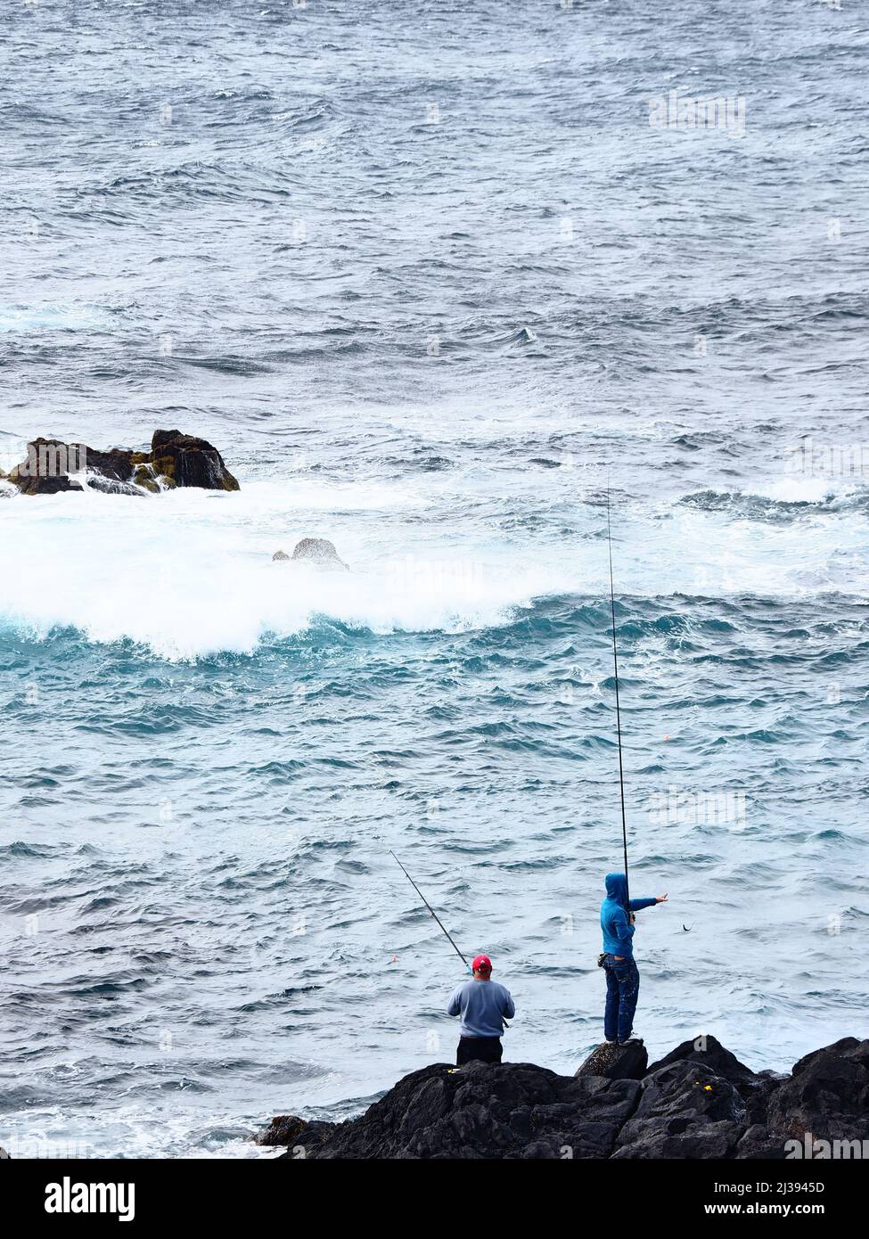 A vertical shot of two men fishing in the sea Stock Photo - Alamy