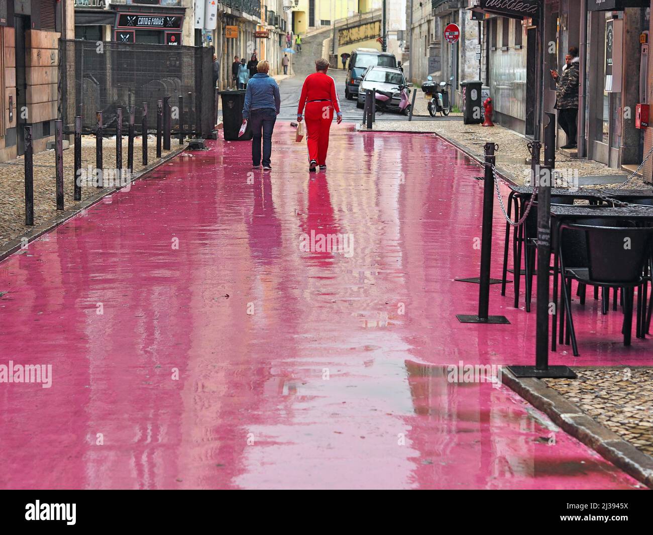 Some people walking on a pink street on a rainy day in Lisbon, Portugal ...