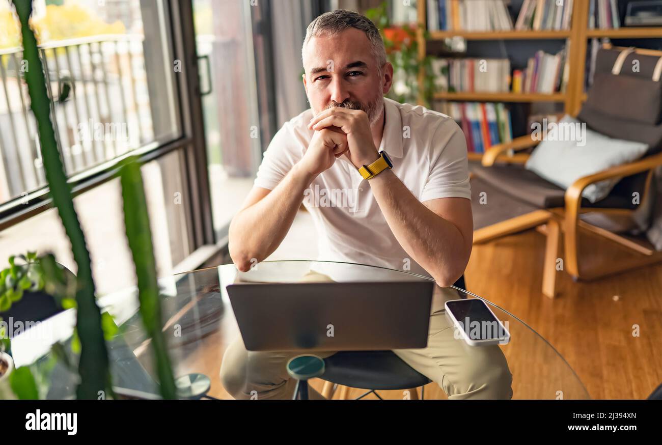 Businessman sitting at desk in bright office using laptop Stock Photo ...