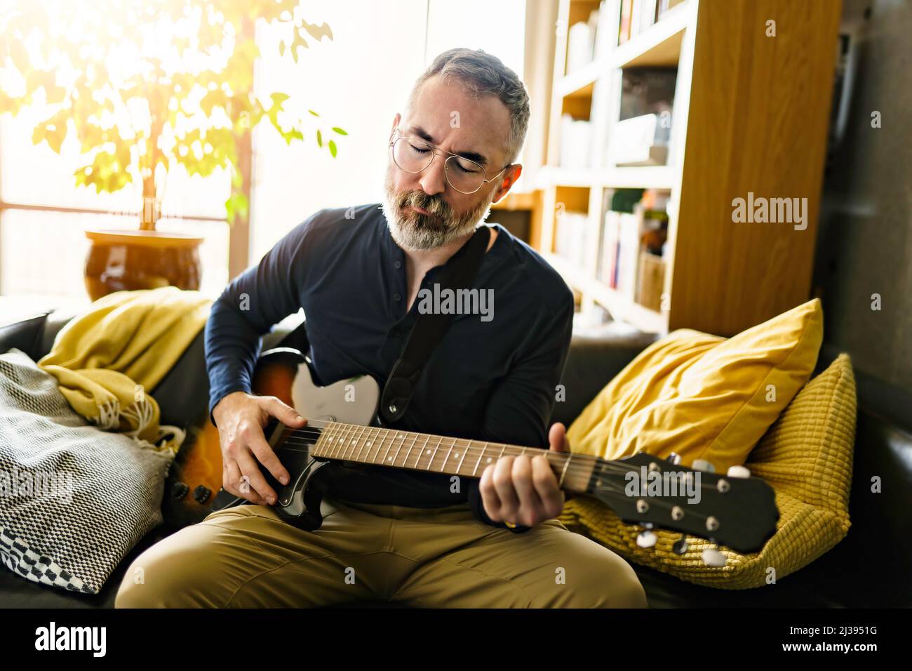 A attractive and relaxed looking man playing the guitar Stock Photo - Alamy