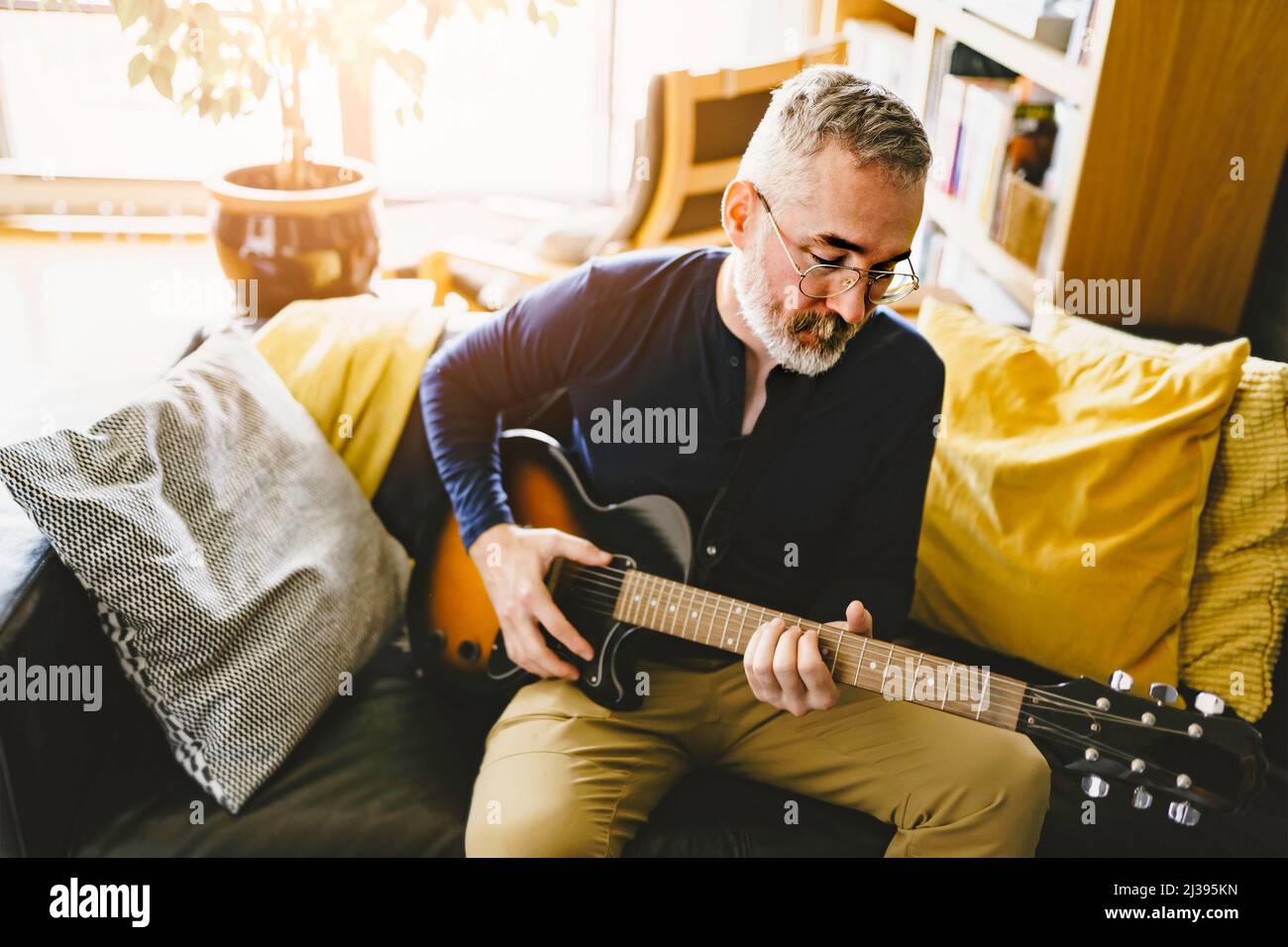 A attractive and relaxed looking man playing the guitar Stock Photo - Alamy
