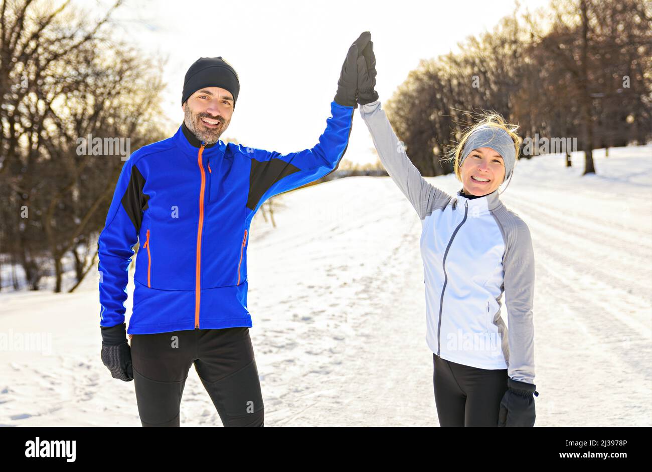 mature couple in the winter running together in nature giving an high ...