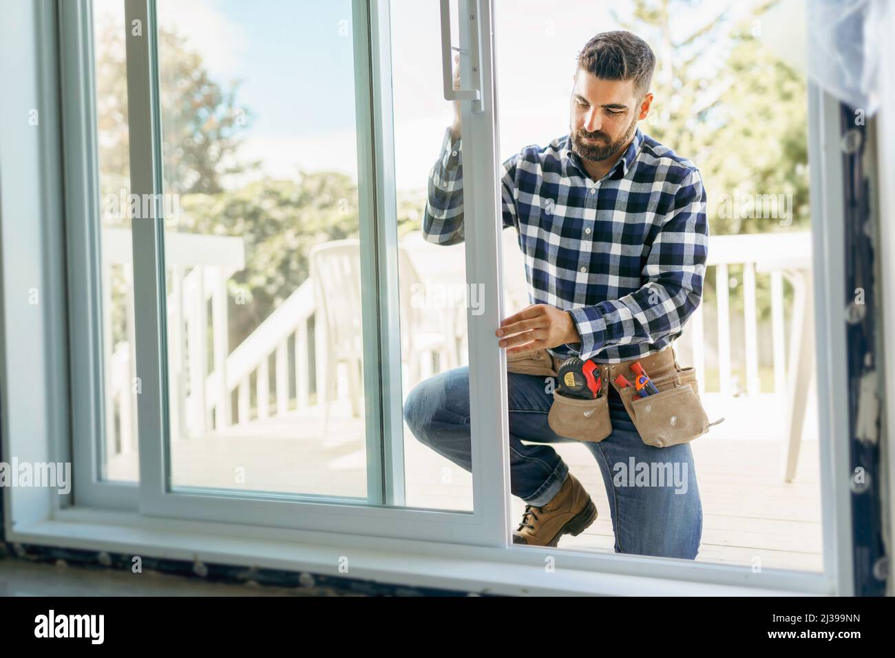handsome young man installing bay window in a new house construction ...