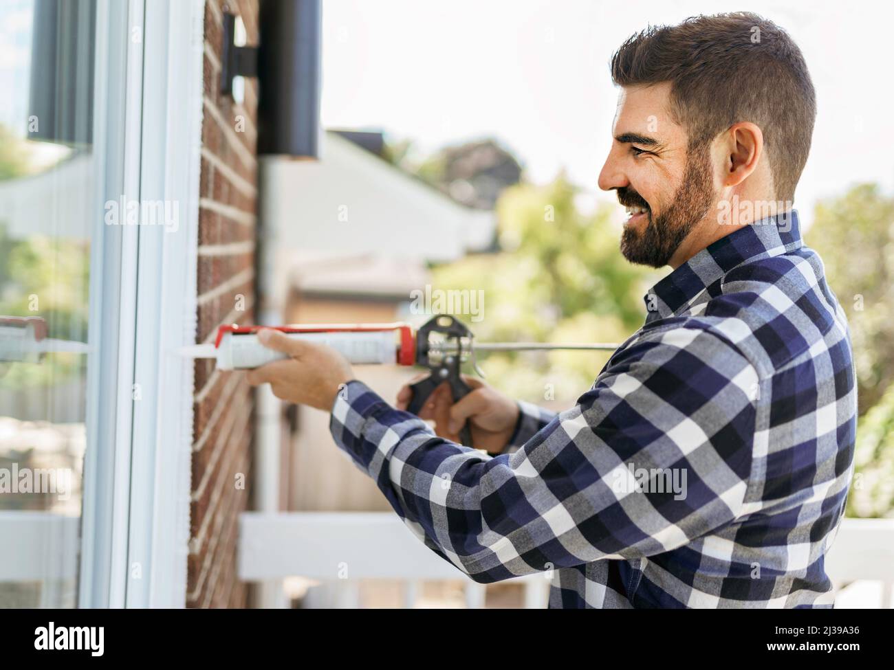 handsome young man installing bay window in a new house construction ...