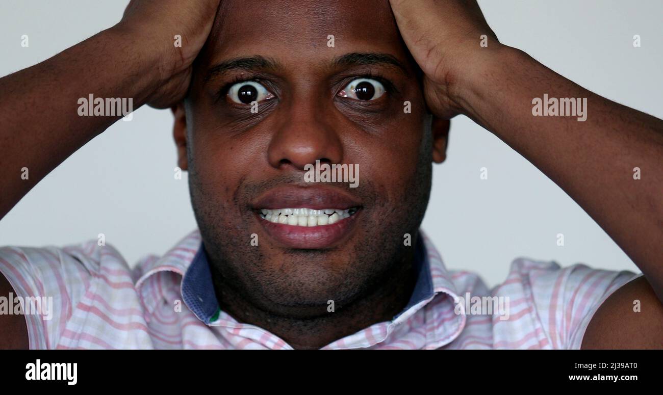 Neurotic anxious black African man looking at camera in desperation and ...