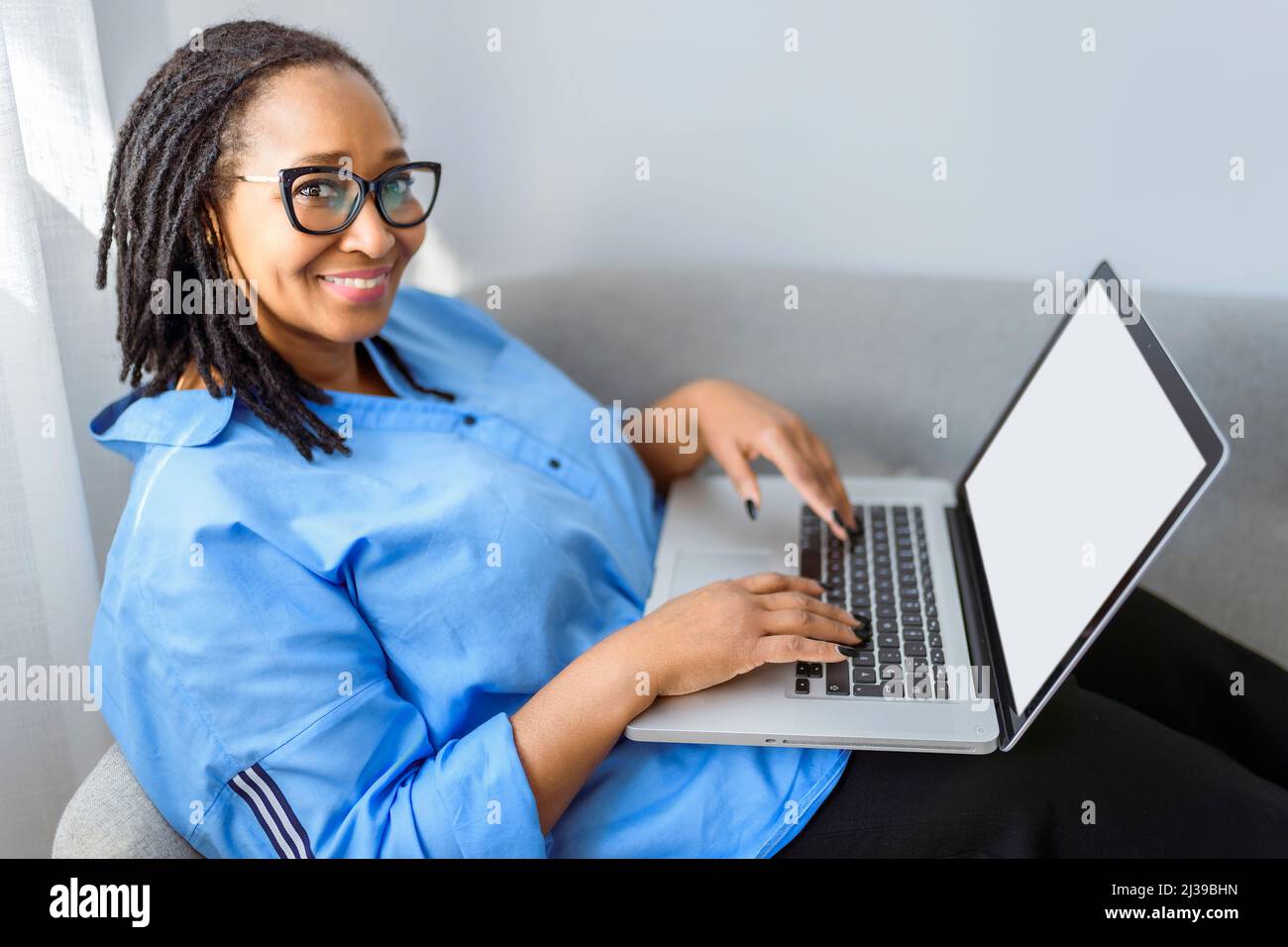 Photo of pretty black woman using laptop at home sofa Stock Photo - Alamy