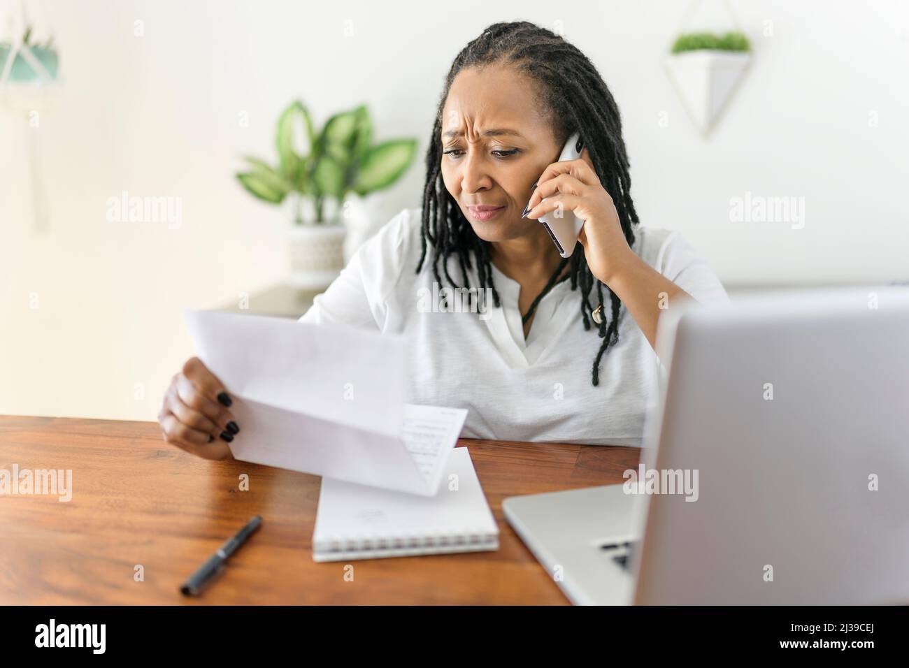 black woman using computer in modern kitchen interior with cellphone on ...