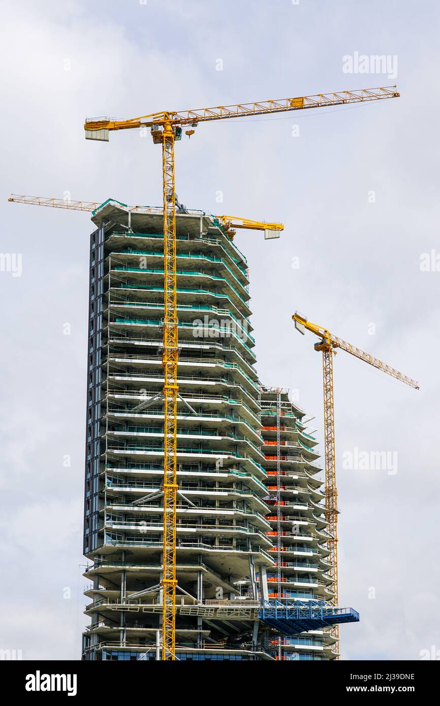 three yellow tower cranes and a fragment of the facade of an unfinished ...