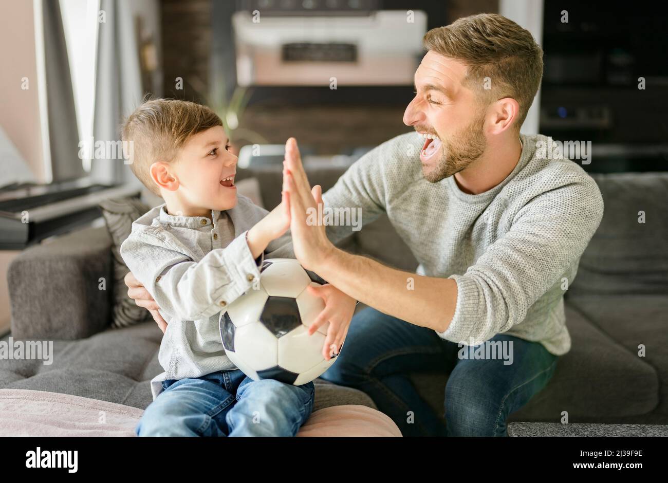 Soccer fans Emotional dad and son cheering with football ball, watching ...