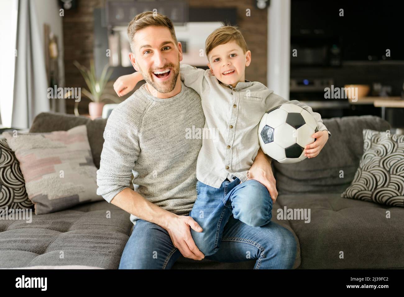 Soccer fans Emotional dad and son cheering with football ball, watching ...