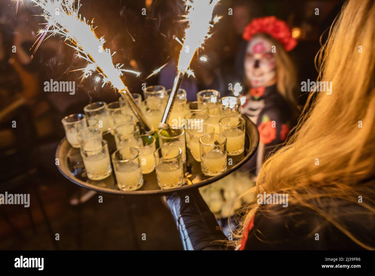 The shots with drink decorated with fireworks on a tray served by a ...