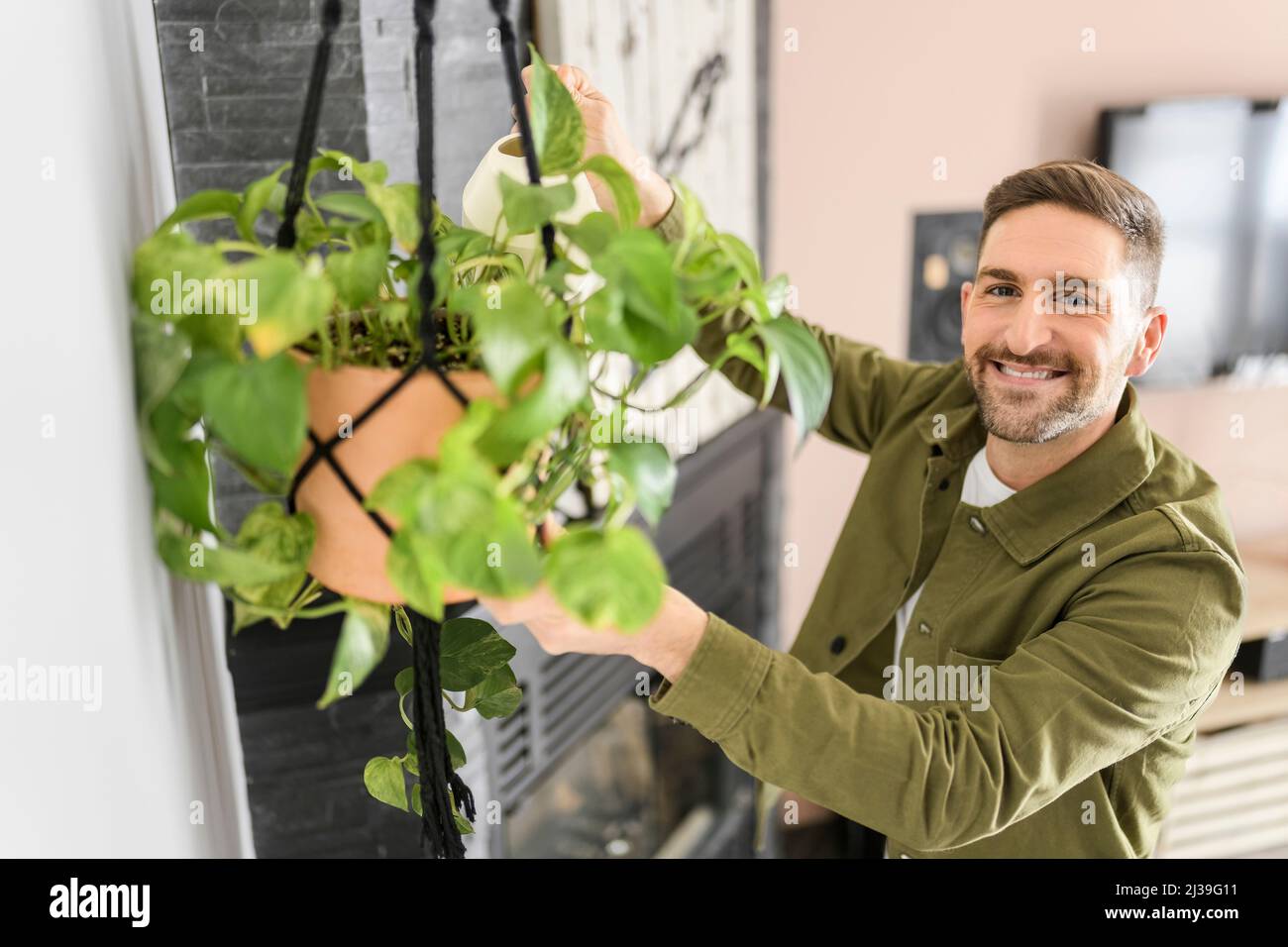 A nice Man spraying water on a house plant and flower with a spray ...