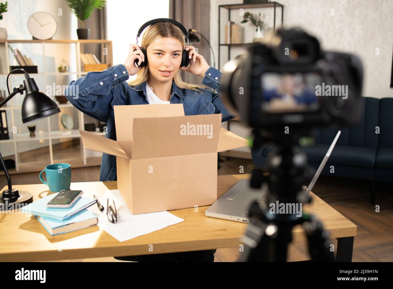 Pretty woman recording video on camera while unpacking box with new ...