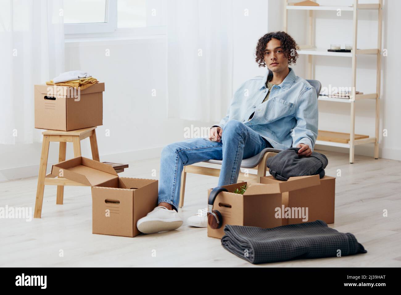 A young man unpacking things from boxes in the room interior Stock ...