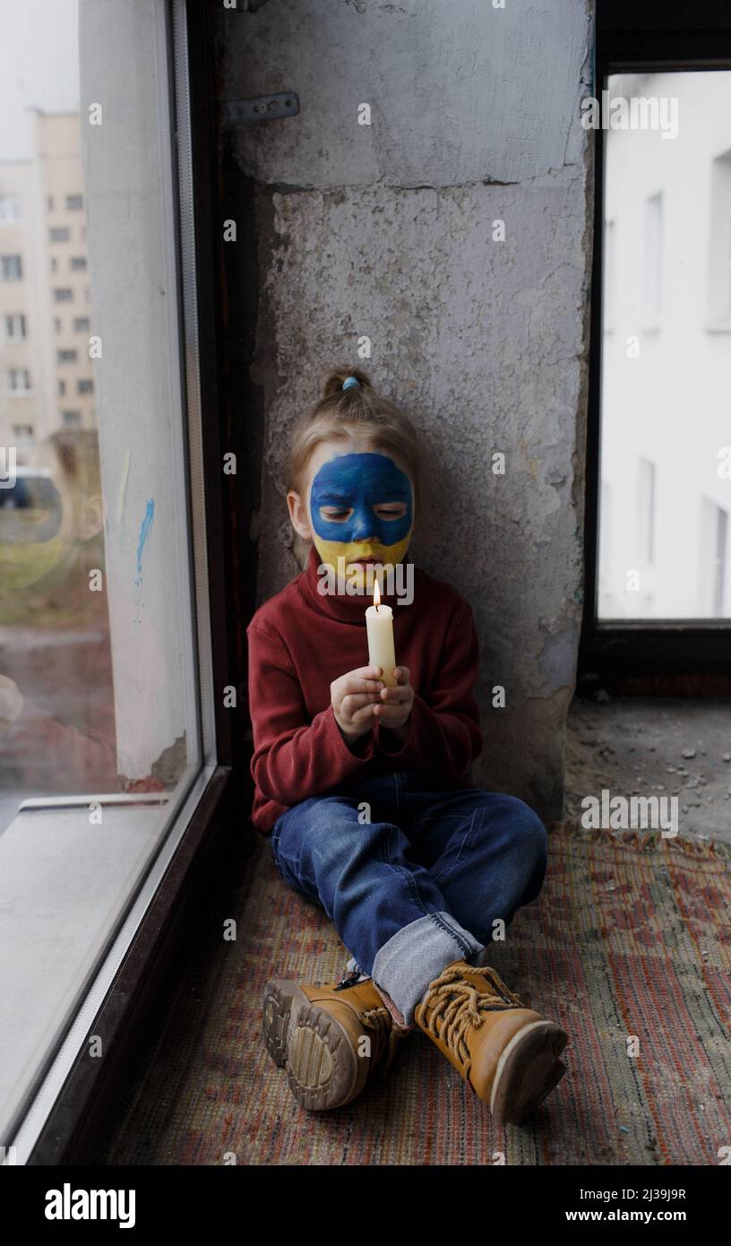 a little girl with a Ukrainian flag painted on her face prays for the ...