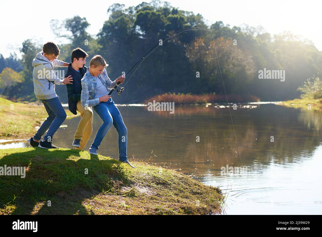 Its a big one. Shot of a group of young boys fishing by a lake Stock ...