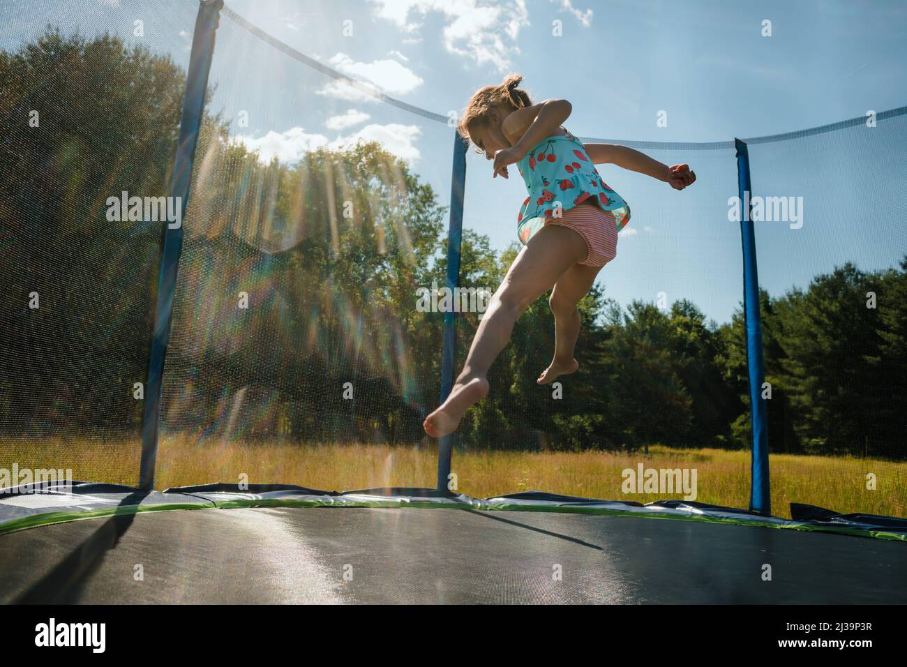 Girl in mid air jumping on trampoline Stock Photo - Alamy