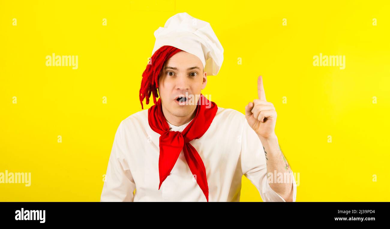 Young chef opening mouth and raising his index finger up on yellow ...
