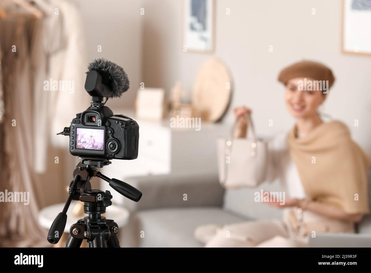 Young female clothes stylist recording video in studio, view on screen ...