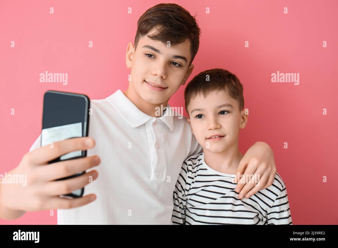 Portrait of cute brothers taking selfie on color background Stock Photo ...