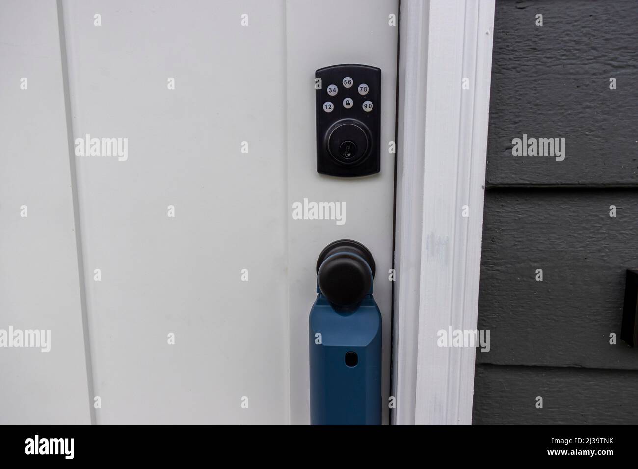View of a white door with keypad entry and a real estate lock box ...