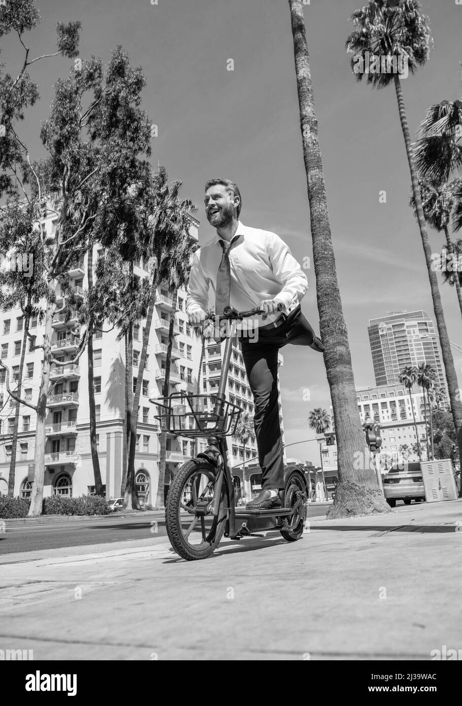 E-scooter on tour. Happy professional man ride e-scooter on sidewalk ...