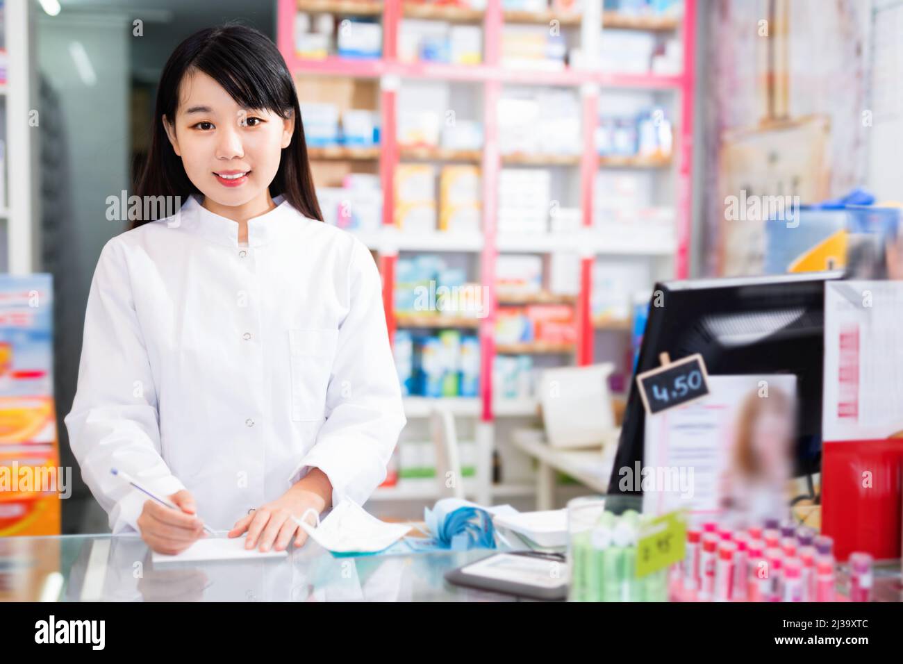 Chinese woman pharmacist keeps track of drugs in interior of pharmacy ...
