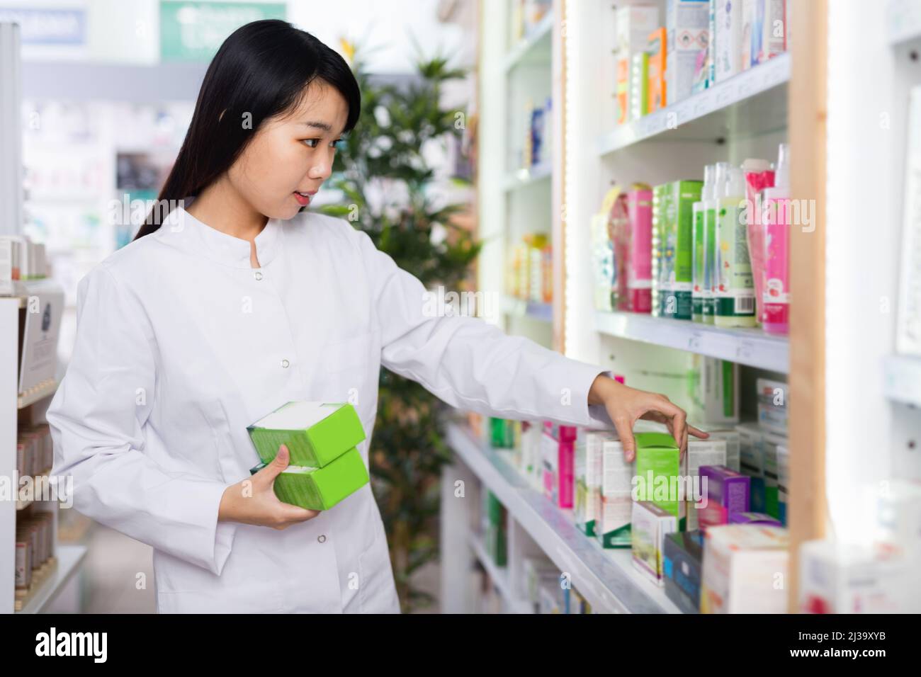 Happy chinese female pharmacist demonstrating assortment of pharmacy ...