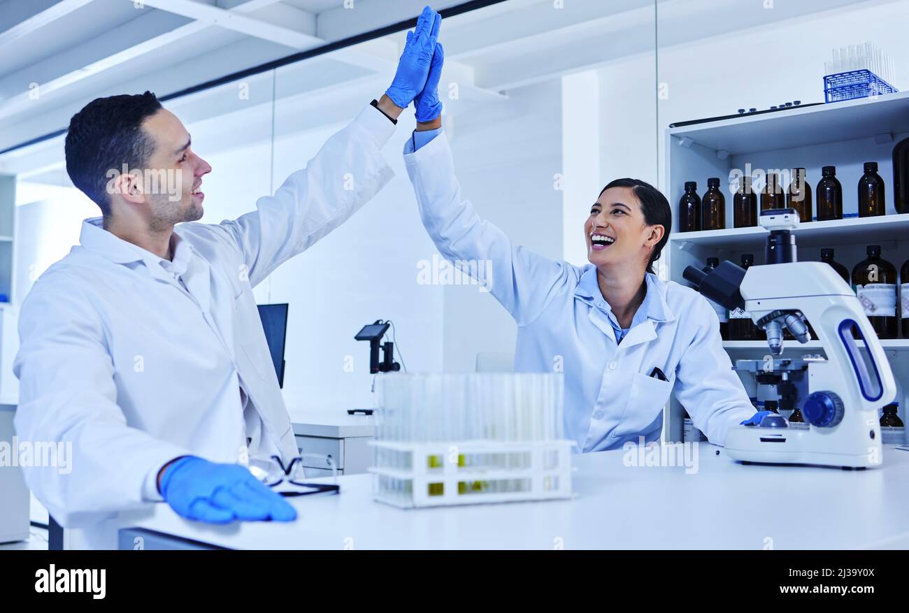 We did it. Cropped shot of two young scientists high fiving while ...