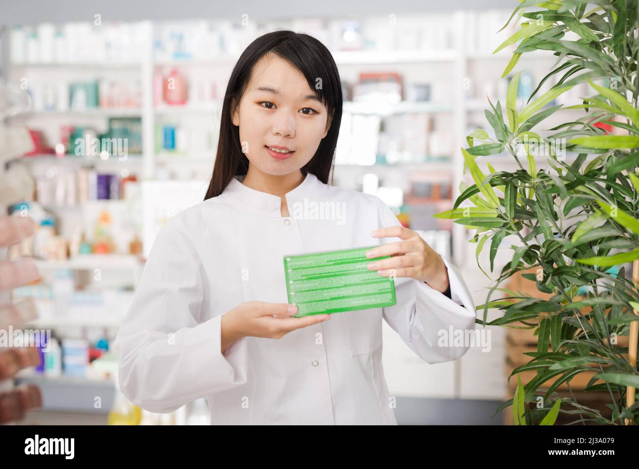Portrait of chinese female pharmacist is standing with medicines in ...
