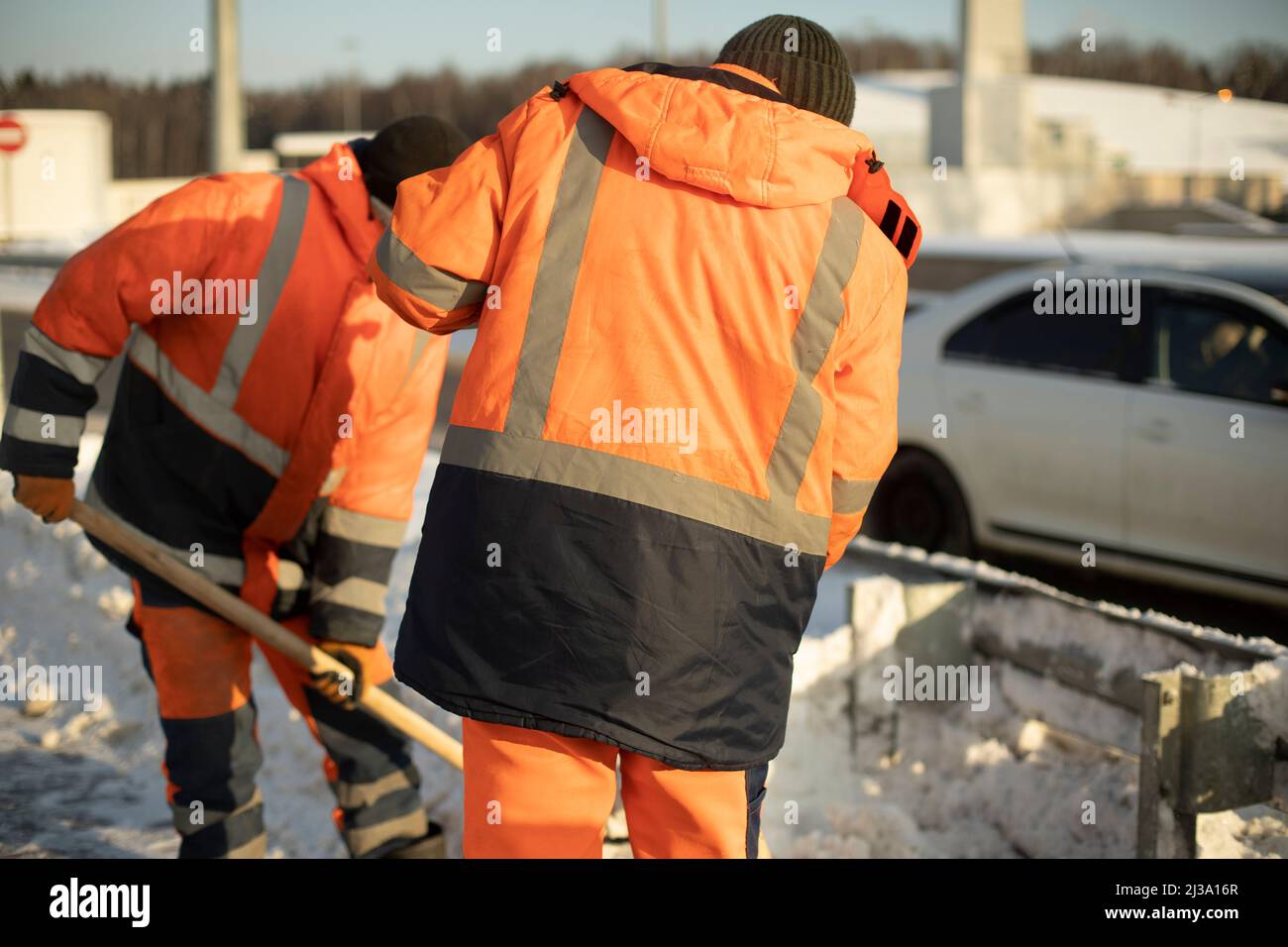 Workers remove snow with shovels. Workers in orange suits. City ...