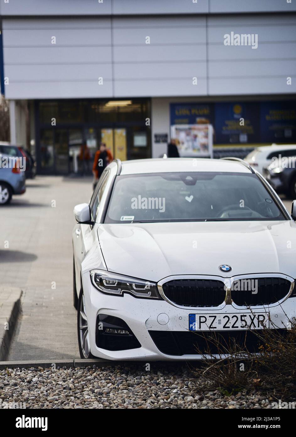 A vertical shot of a parked white BMW car in a parking lot of a ...