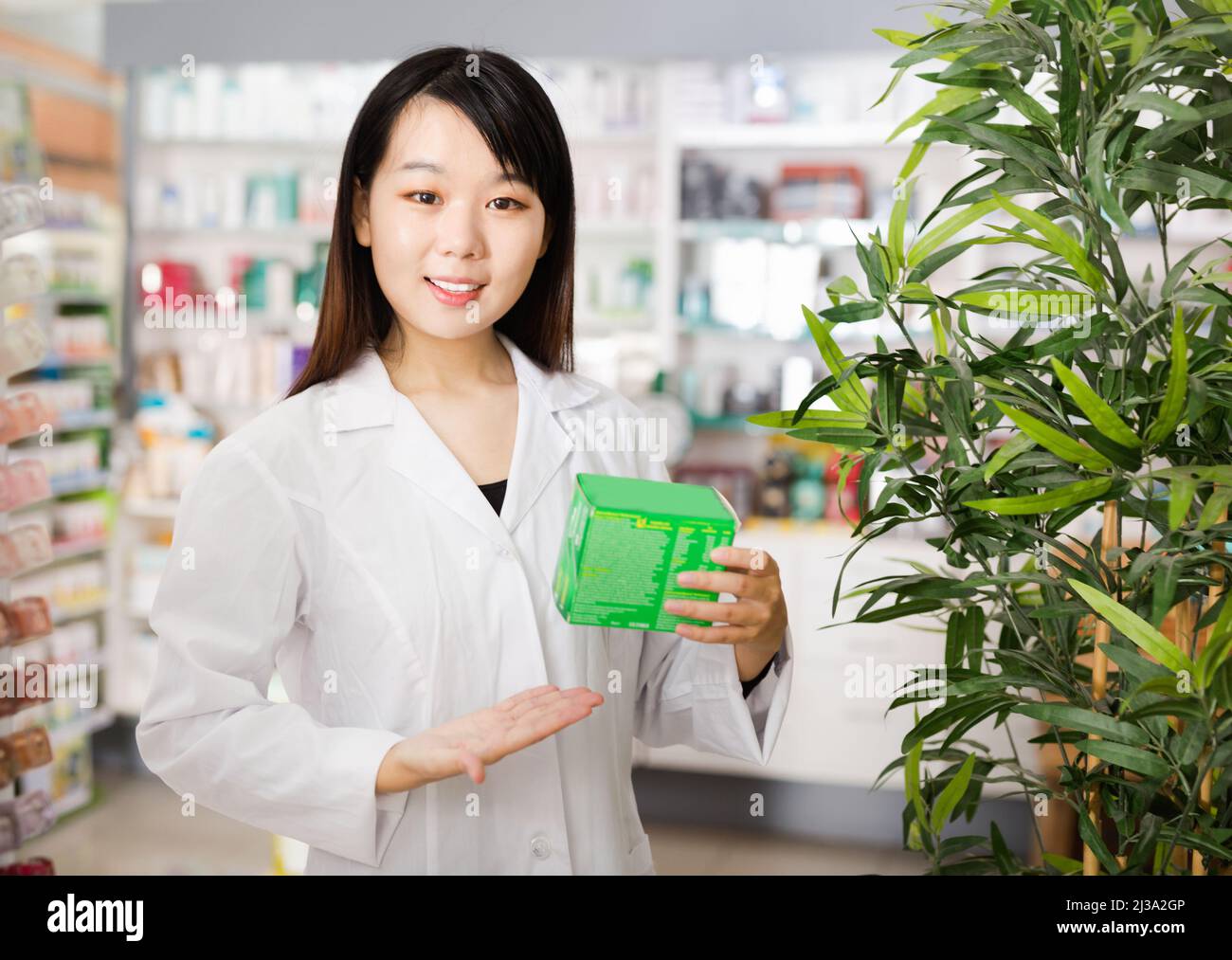 Happy chinese female pharmacist demonstrating assortment of pharmacy ...