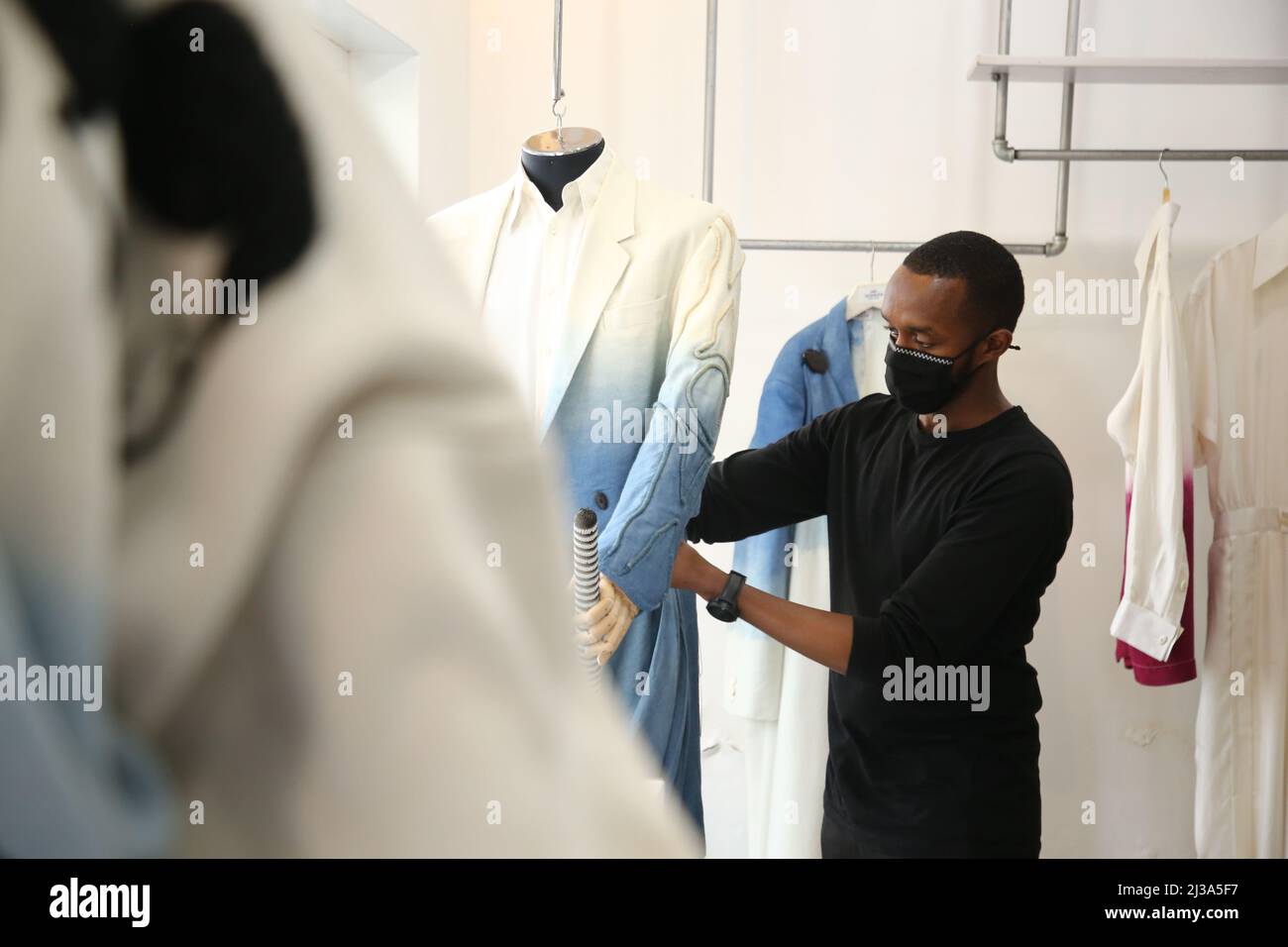 Kigali. 1st Apr, 2022. A staff member arranges clothes in Moshions shop ...