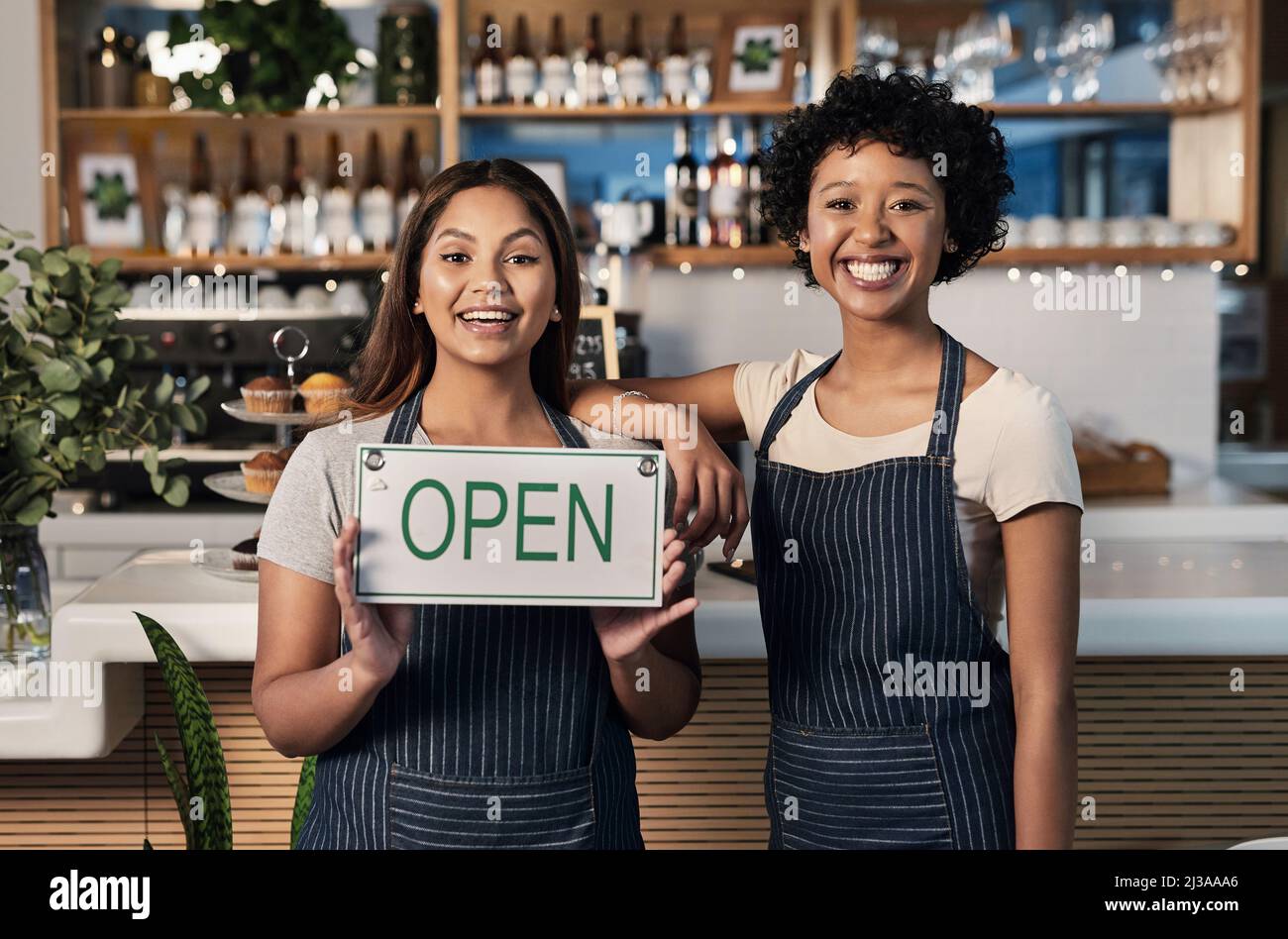Get excited - we are opening soon. Portrait of two young women holding ...