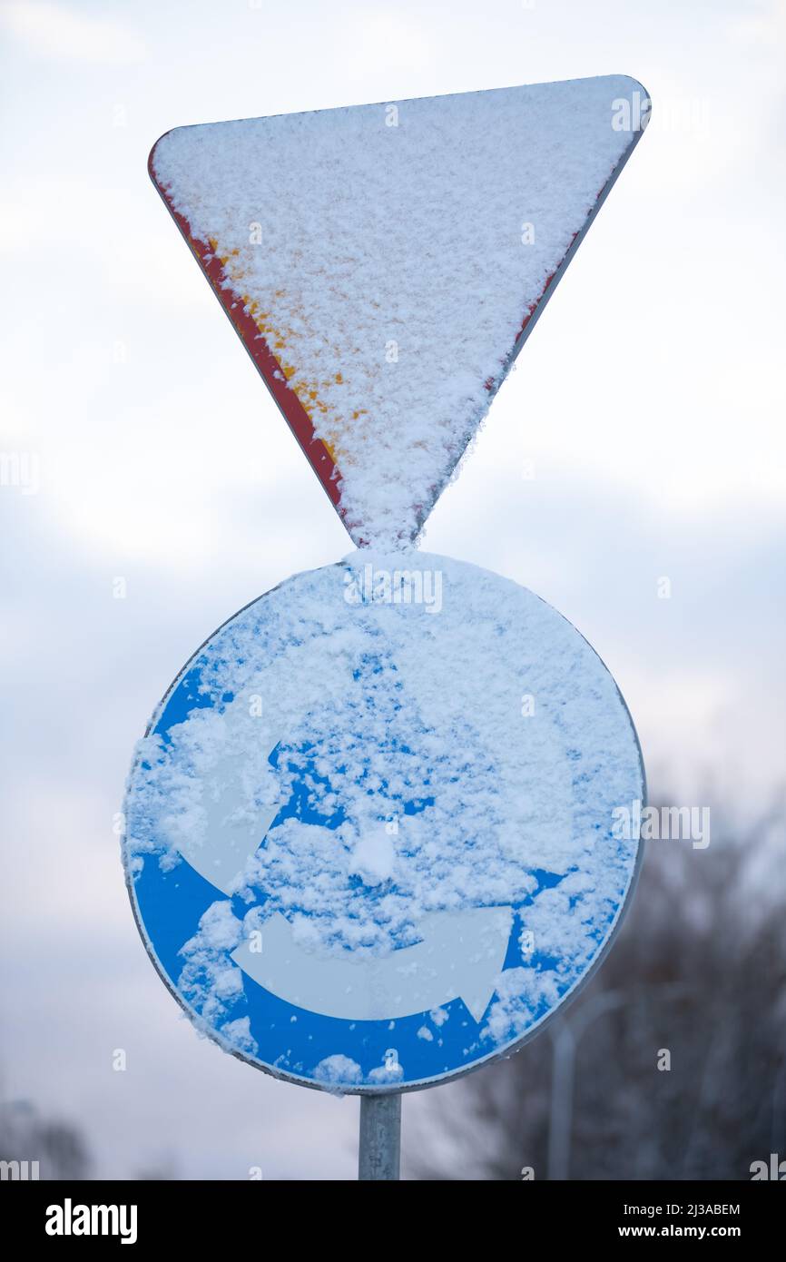 Snowy road sign, intersection with circular traffic Stock Photo - Alamy