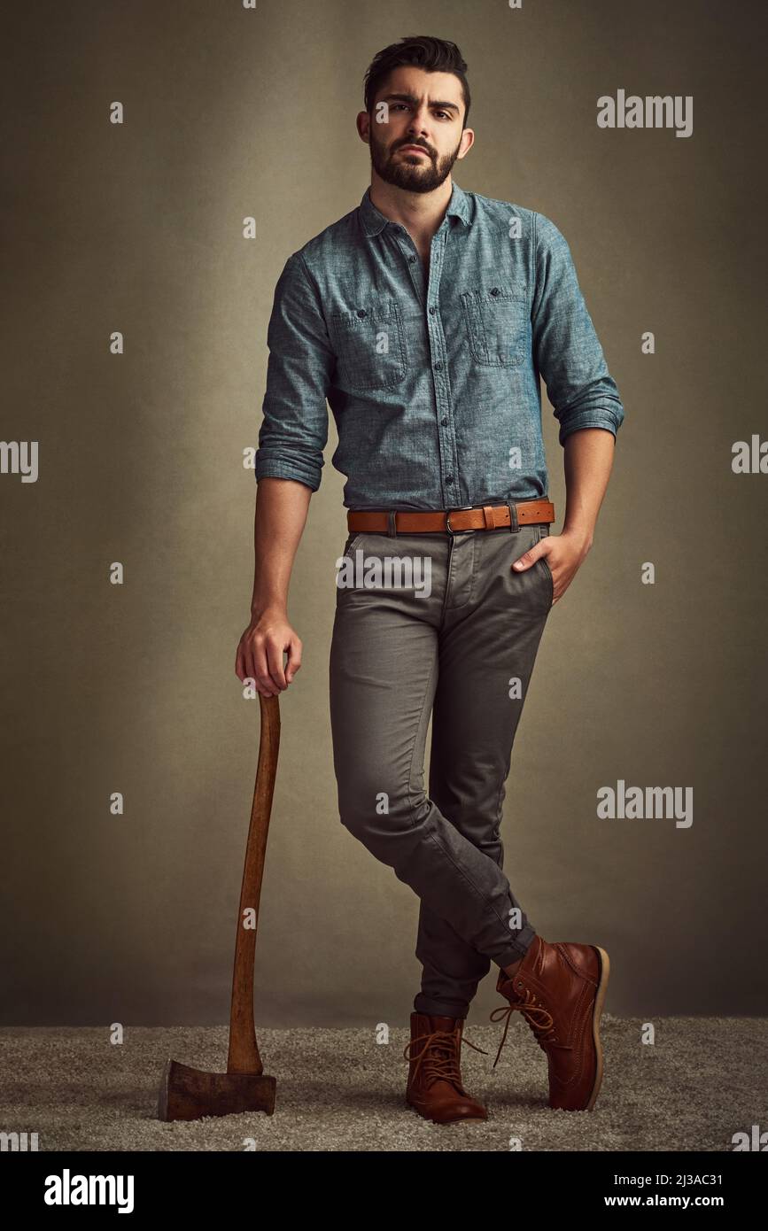 Dashing and daring. Studio shot of a young man posing with an axe ...