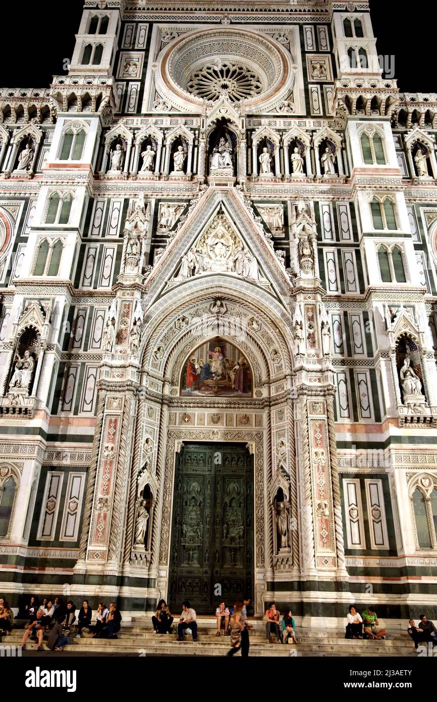 Visitors and local sitting on the steps of the Duomo at night. It is ...