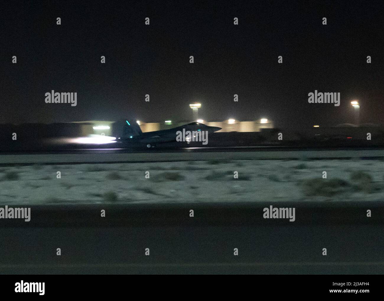 A F-22 Raptor takes off with afterburner during a night mission at Al ...
