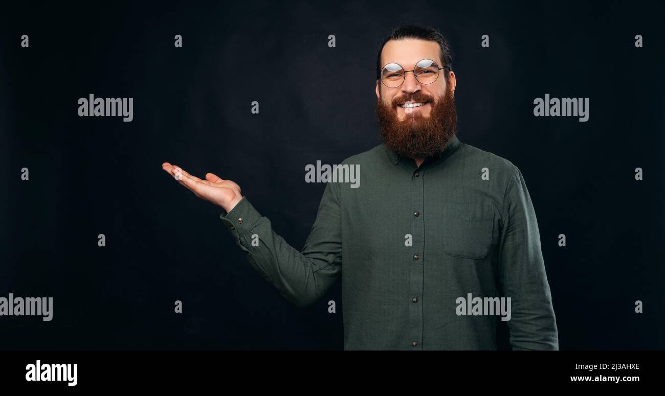 Panorama photo of a bearded man holding hand up over black background ...
