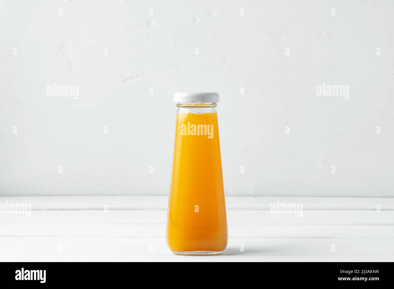 Small glass bottle of fresh juice on white background Stock Photo - Alamy