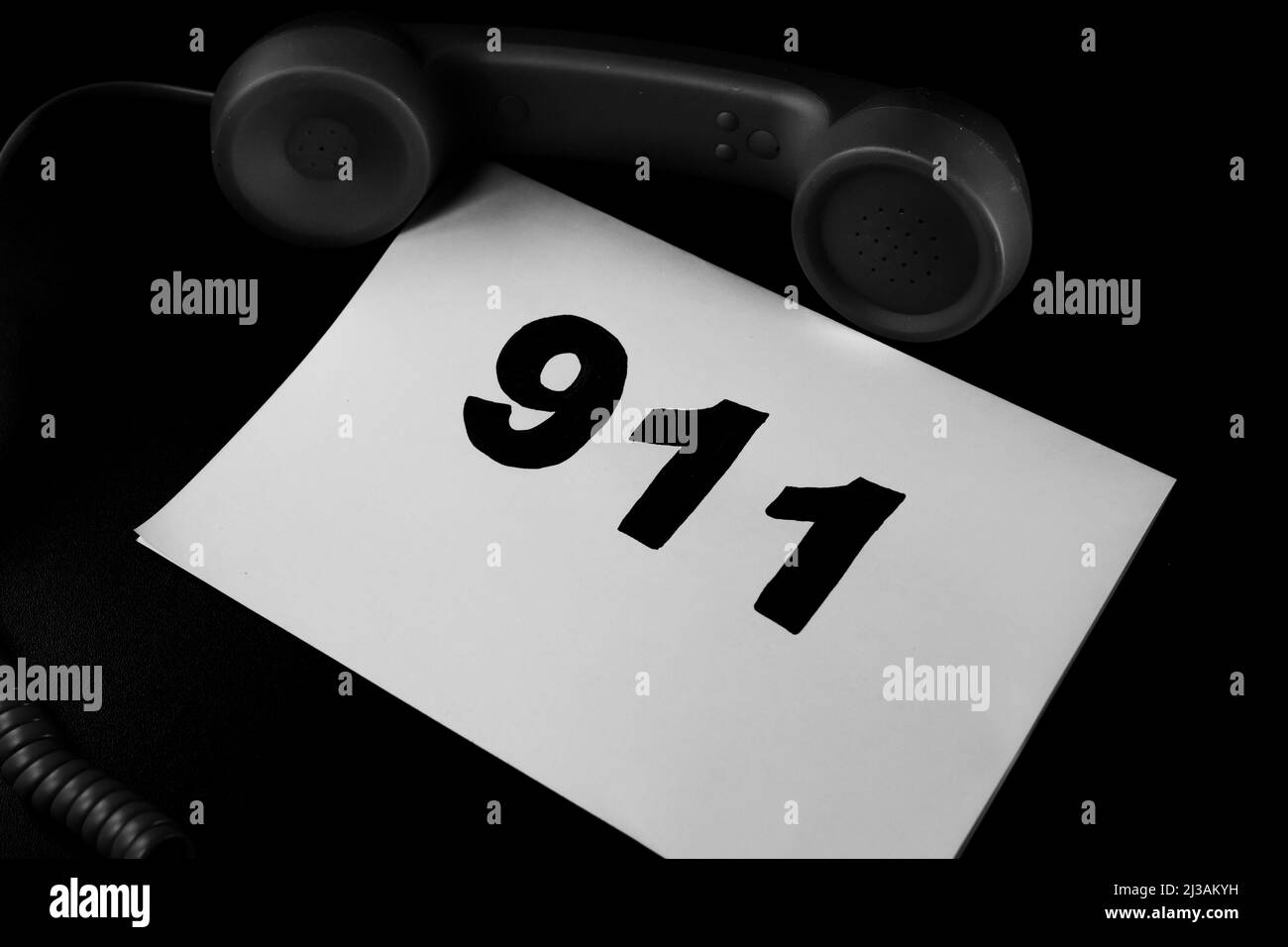 A 911 text on a paper and a phone isolated on a black background Stock ...