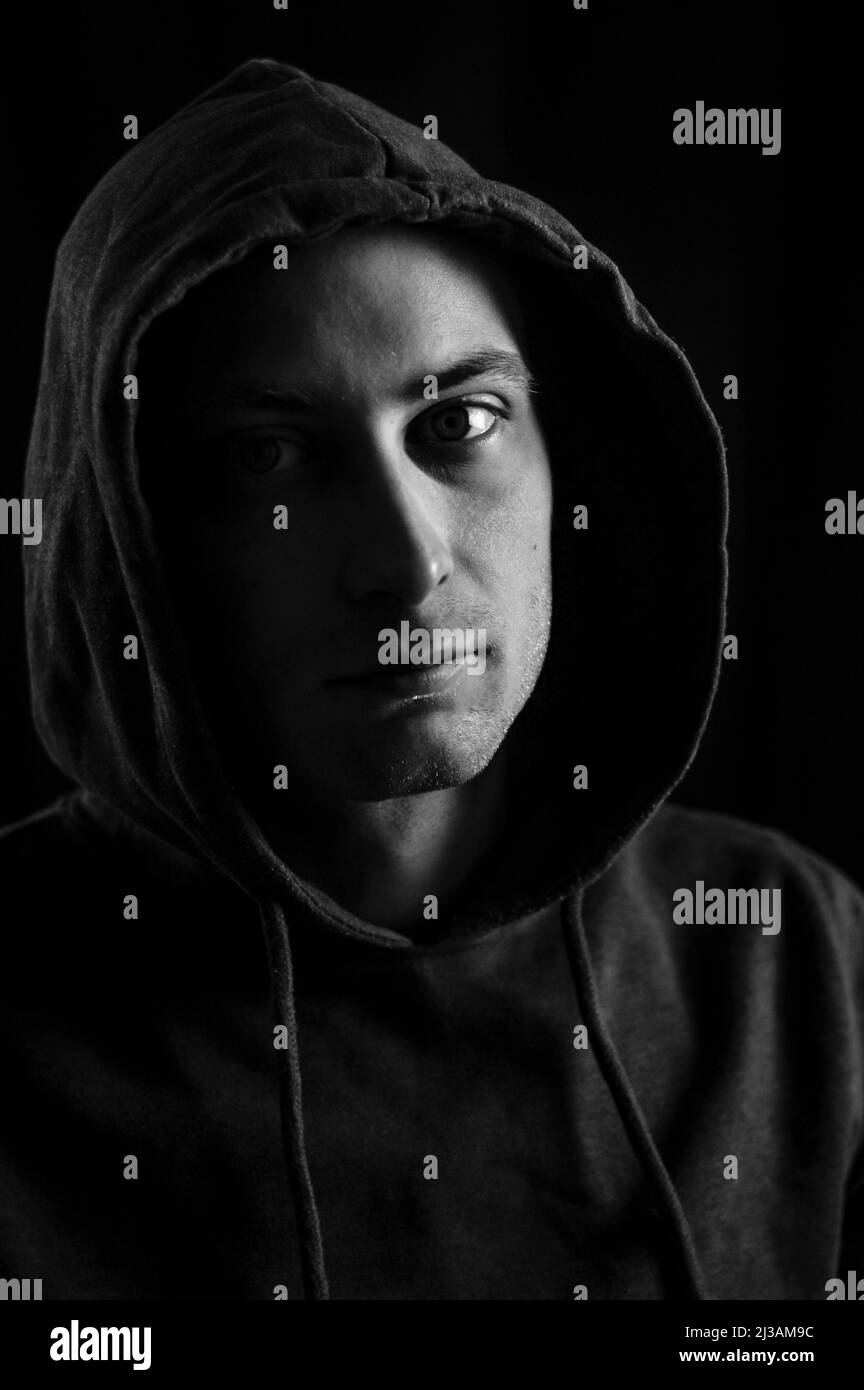Portrait in black and white of a young man with a hood on his head ...